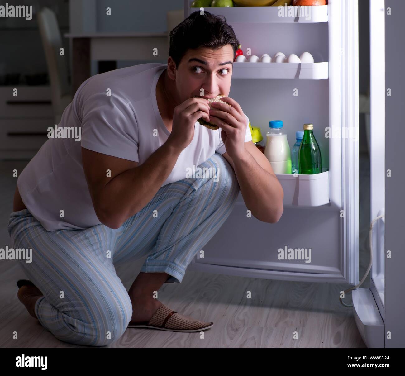 The man at the fridge eating at night Stock Photo - Alamy