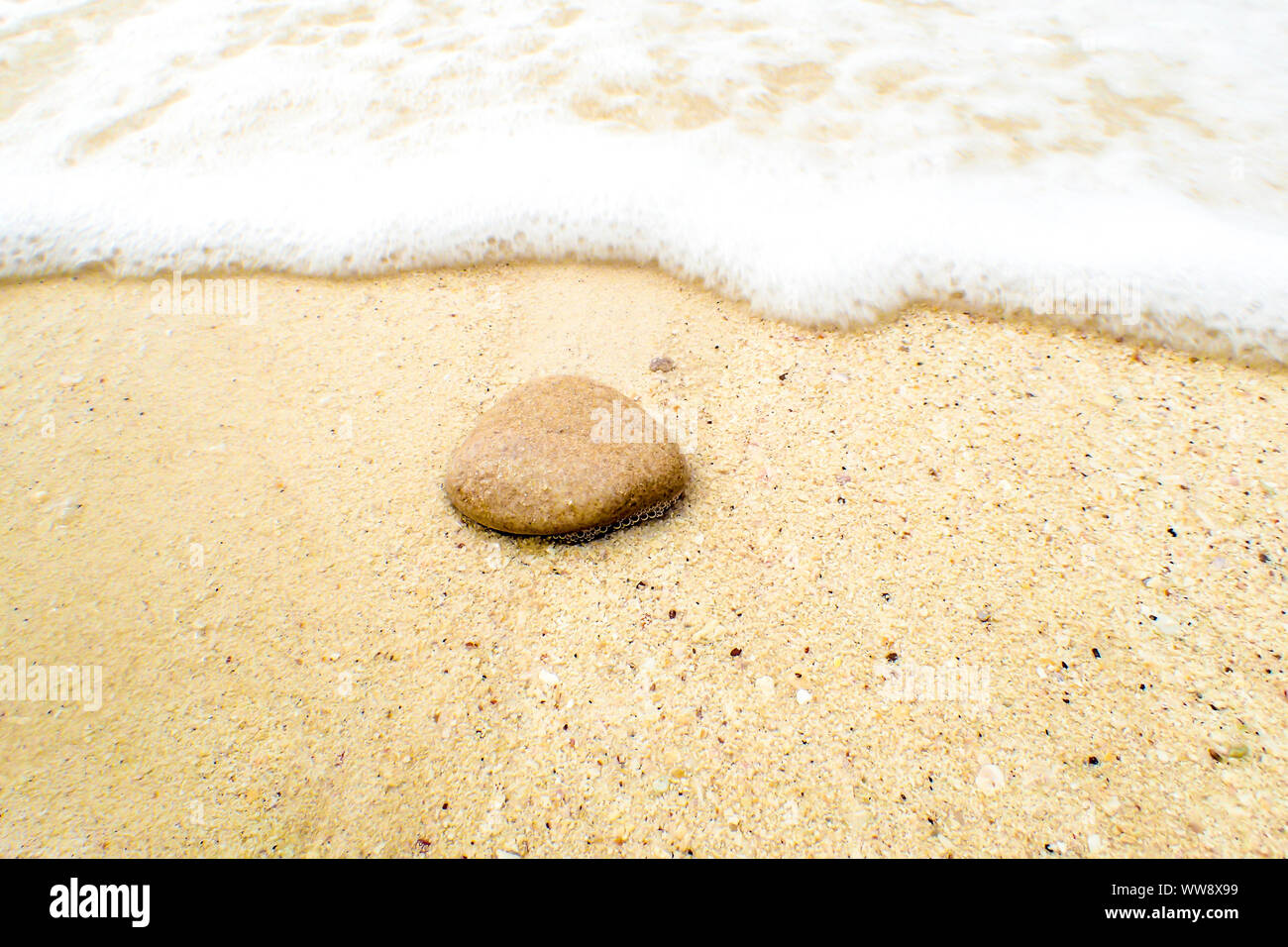 Ocean sea water rushing in to sandy beach shore on a cloudy blue sky ...