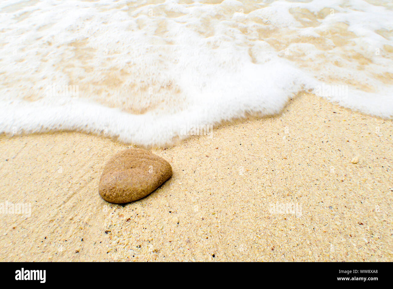 Ocean sea water rushing in to sandy beach shore on a cloudy blue sky ...