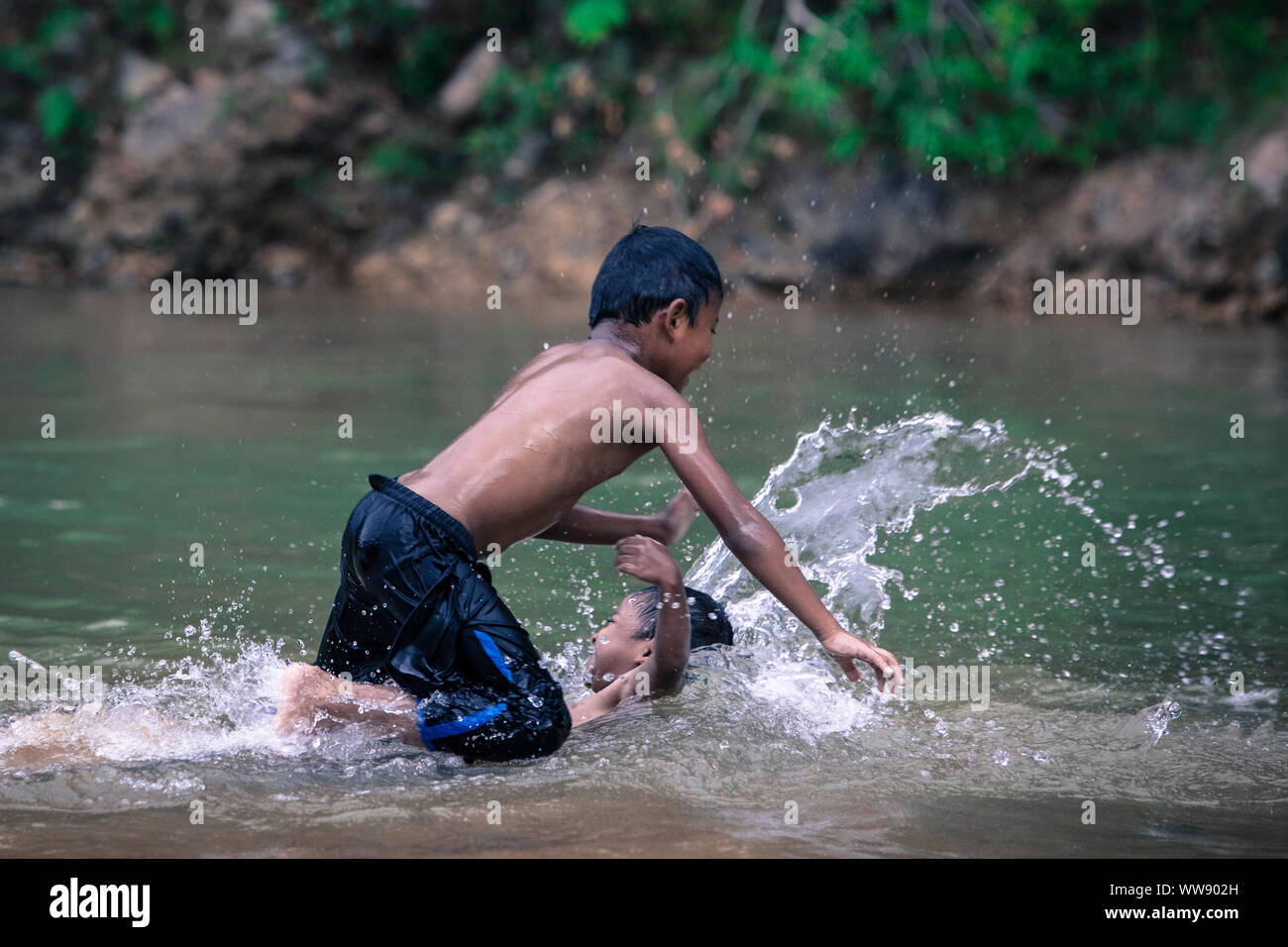 Two kids playing in the river close to riverbank at Sungai Lembing ...