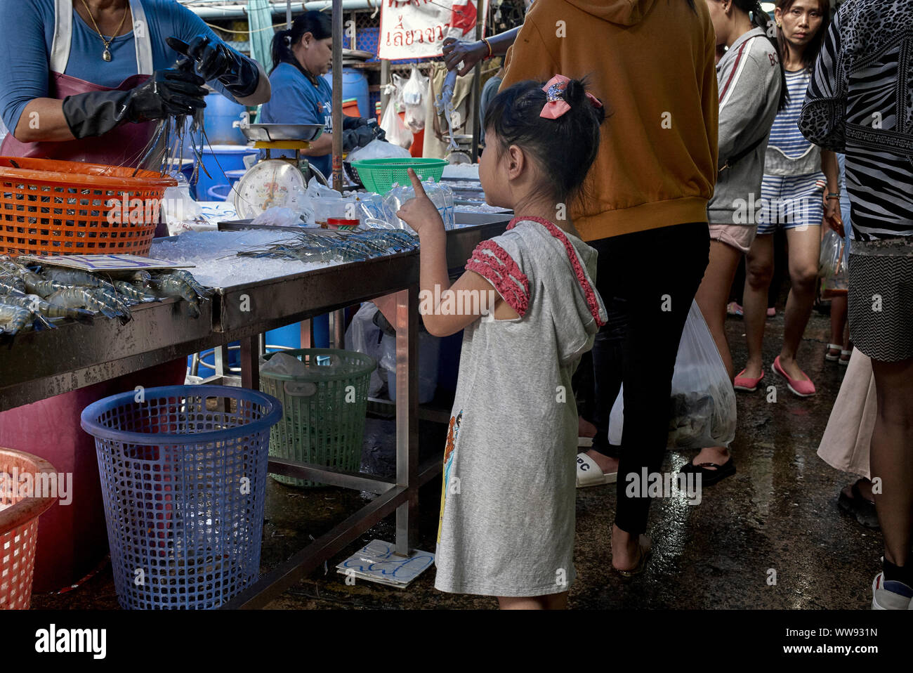 Child using her finger to order one item from a fish vendor. Thailand ...