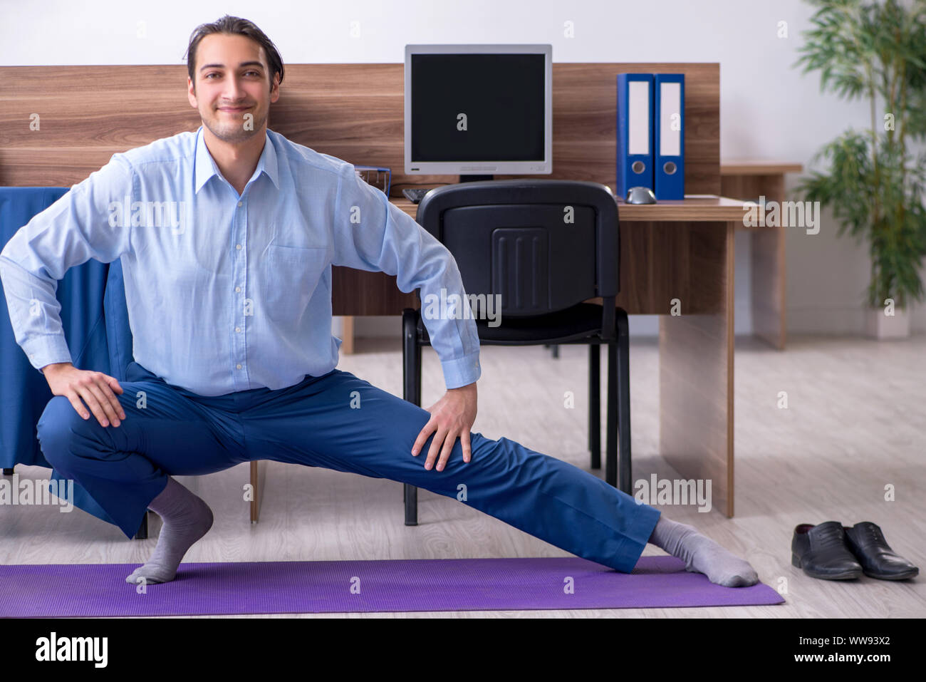The young handsome businessman doing exercises at workplace Stock Photo ...