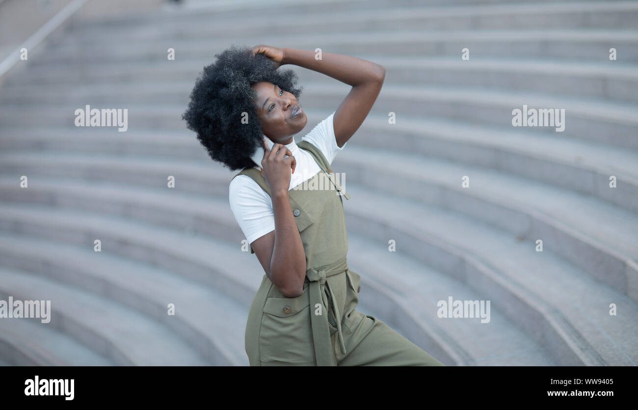 Happy young black woman calling by mobile phone outdoors in the city ...