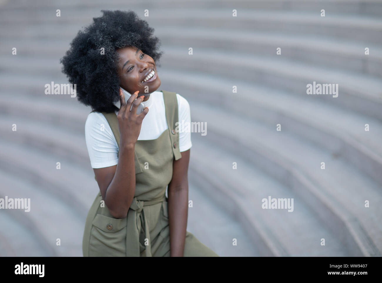 Happy young black woman calling by mobile phone outdoors in the city ...