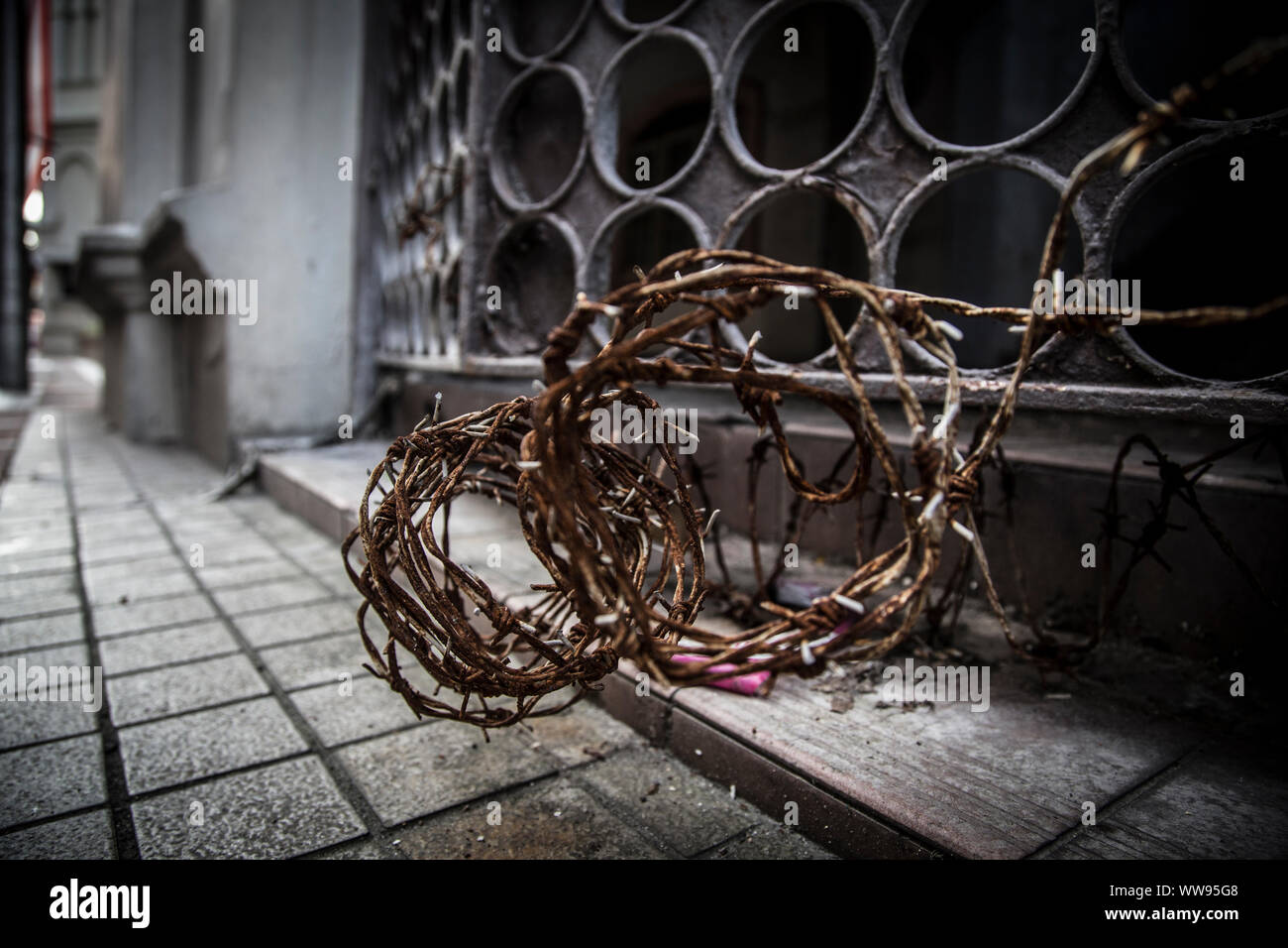 Sharp security barb wire fence barrier mesh next to colonial building ...
