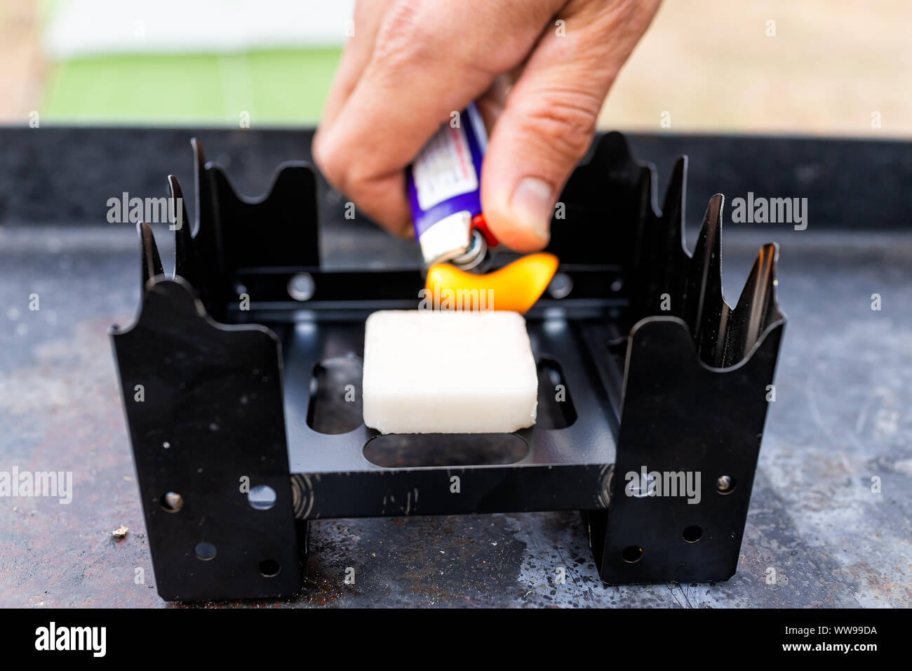 Campsite with closeup of hand light camp stove hexamine fuel tablet in ...