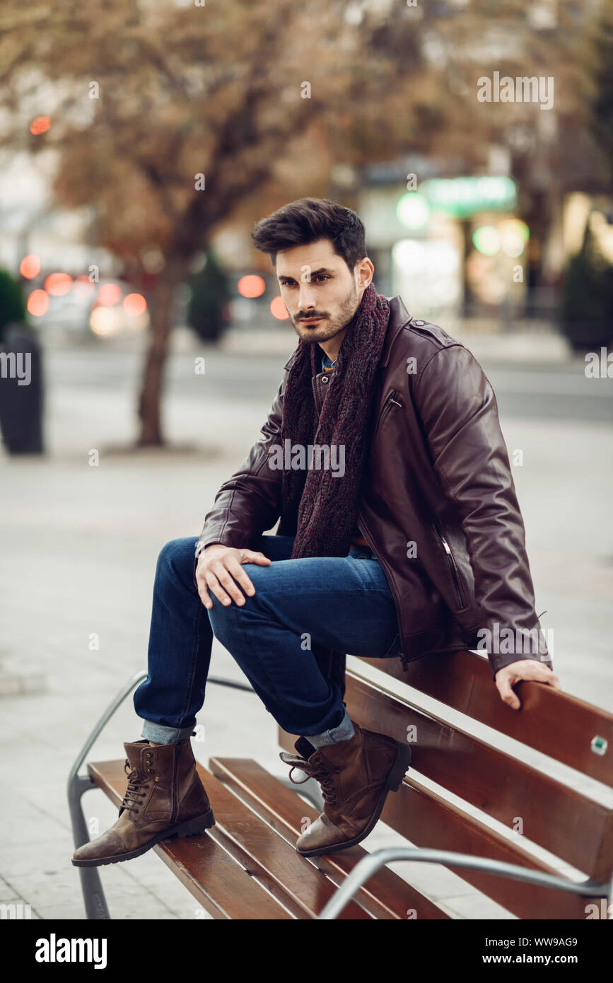 Thoughtful young man sitting on an urban bench Stock Photo - Alamy