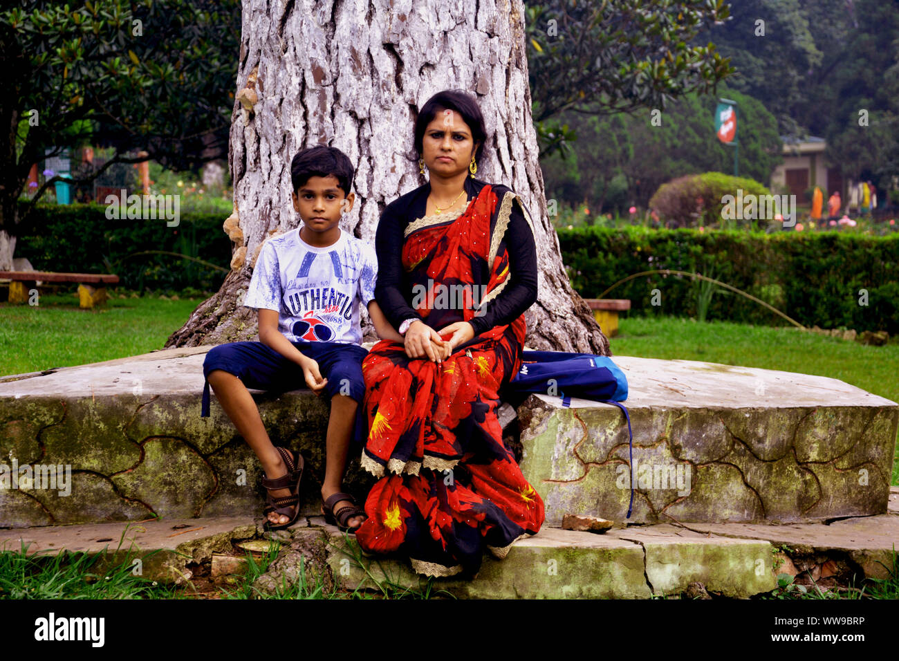 Child and mother sitting on a round concrete platform beneath a big ...