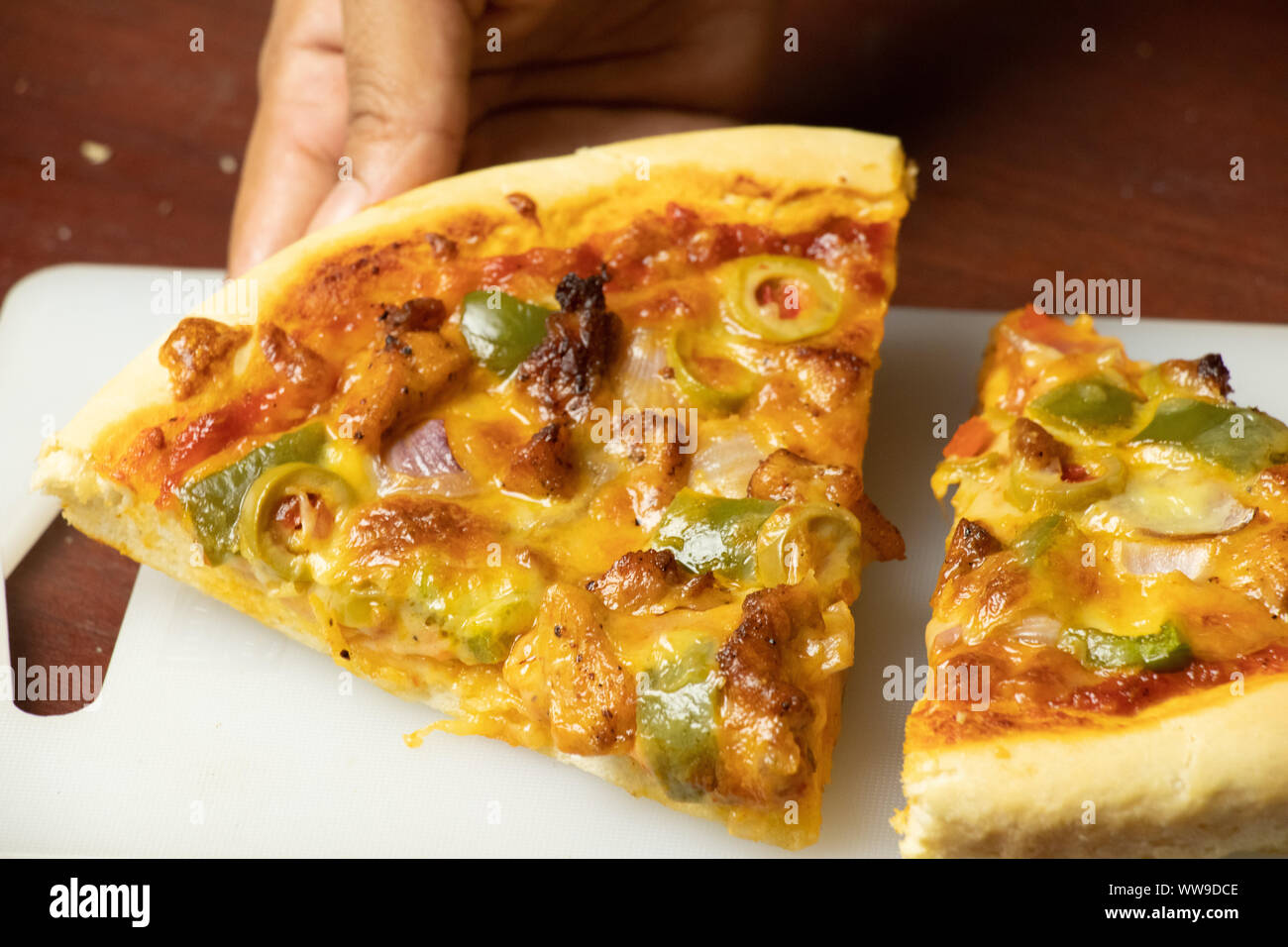 Pan Pizza slice take from hand side view with dark brown wood Stock ...