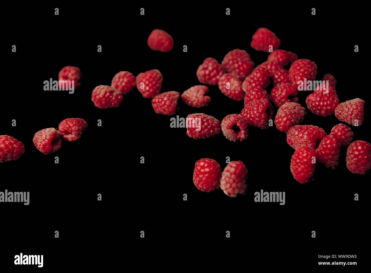 berries of red raspberries in a bunch lie isolated on a black ...