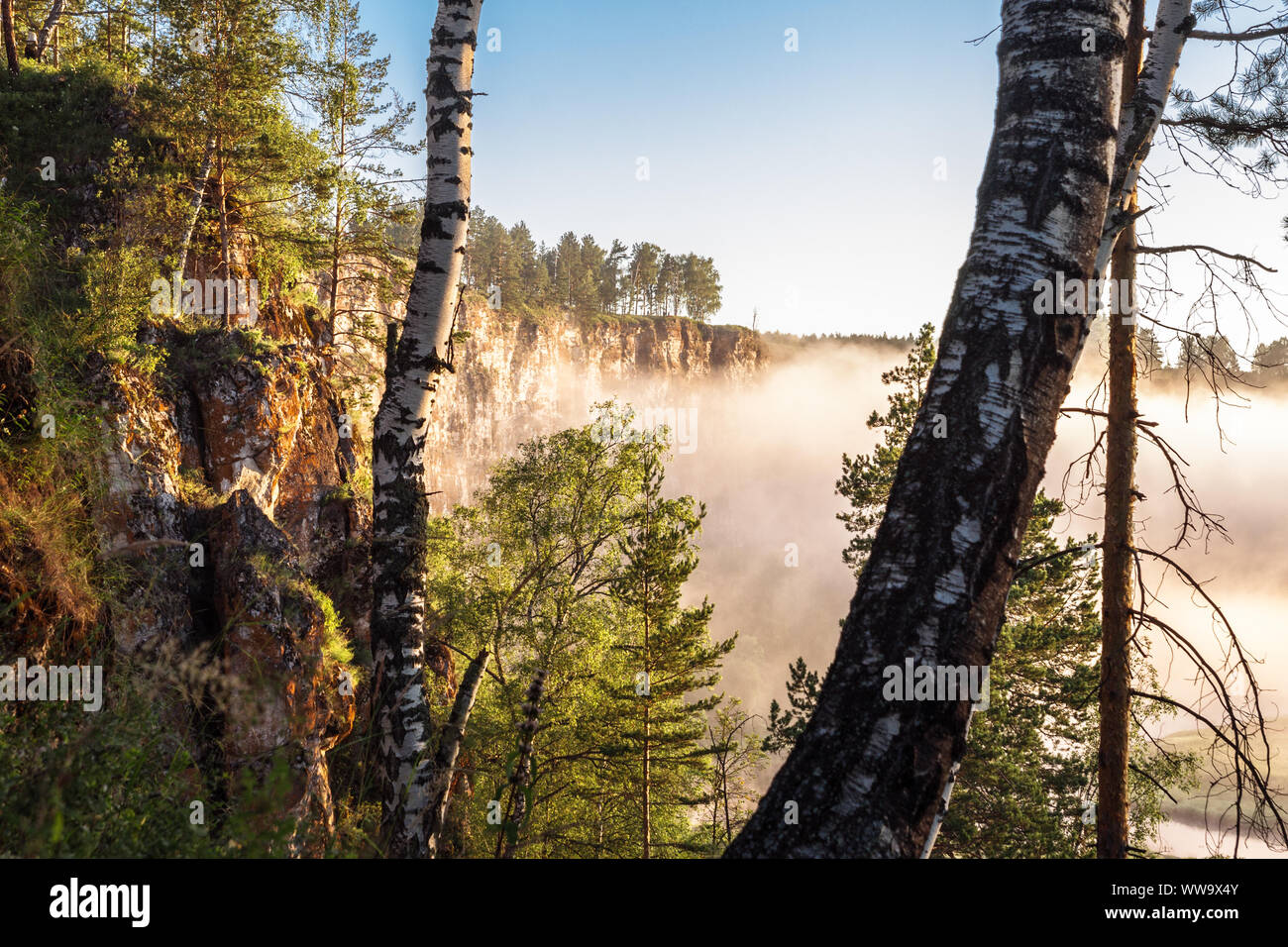View on stone precipice and fog above the river through trees Stock ...