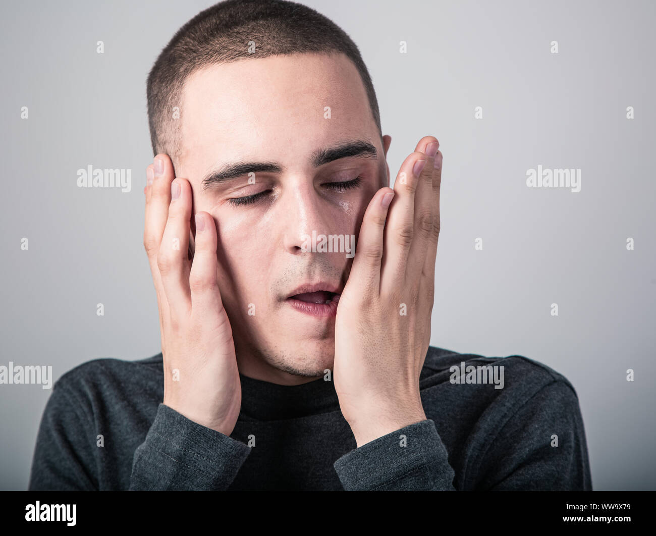 Unhappy crying man with dropping tears on the face touching the face ...