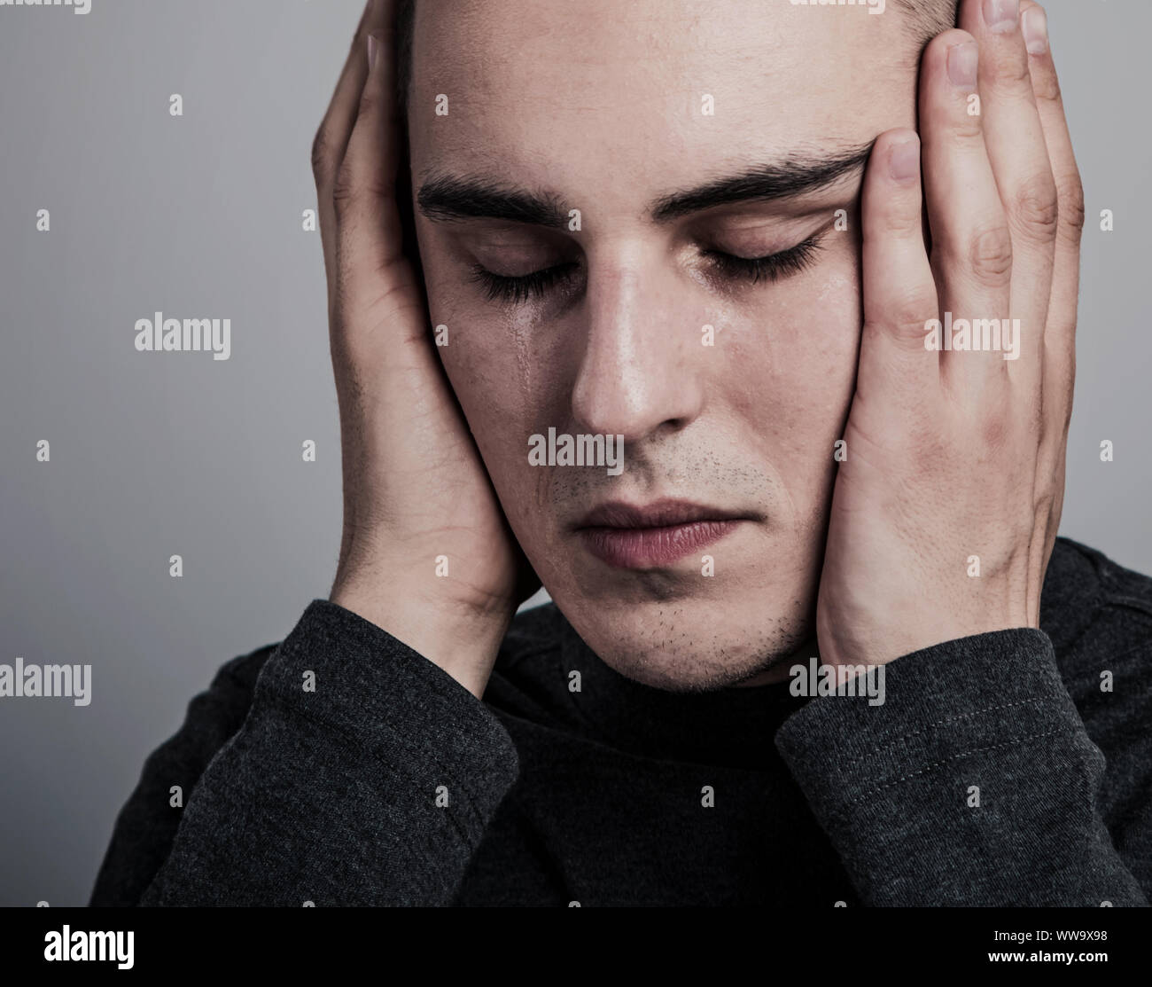 Crying man with dropping tears on the face with headache holding the ...