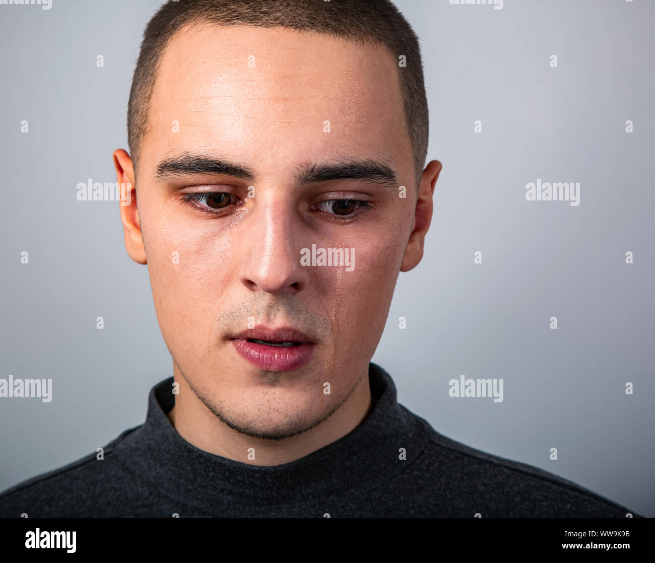 Unhappy crying young man with dropping tears on the face. Closeup ...