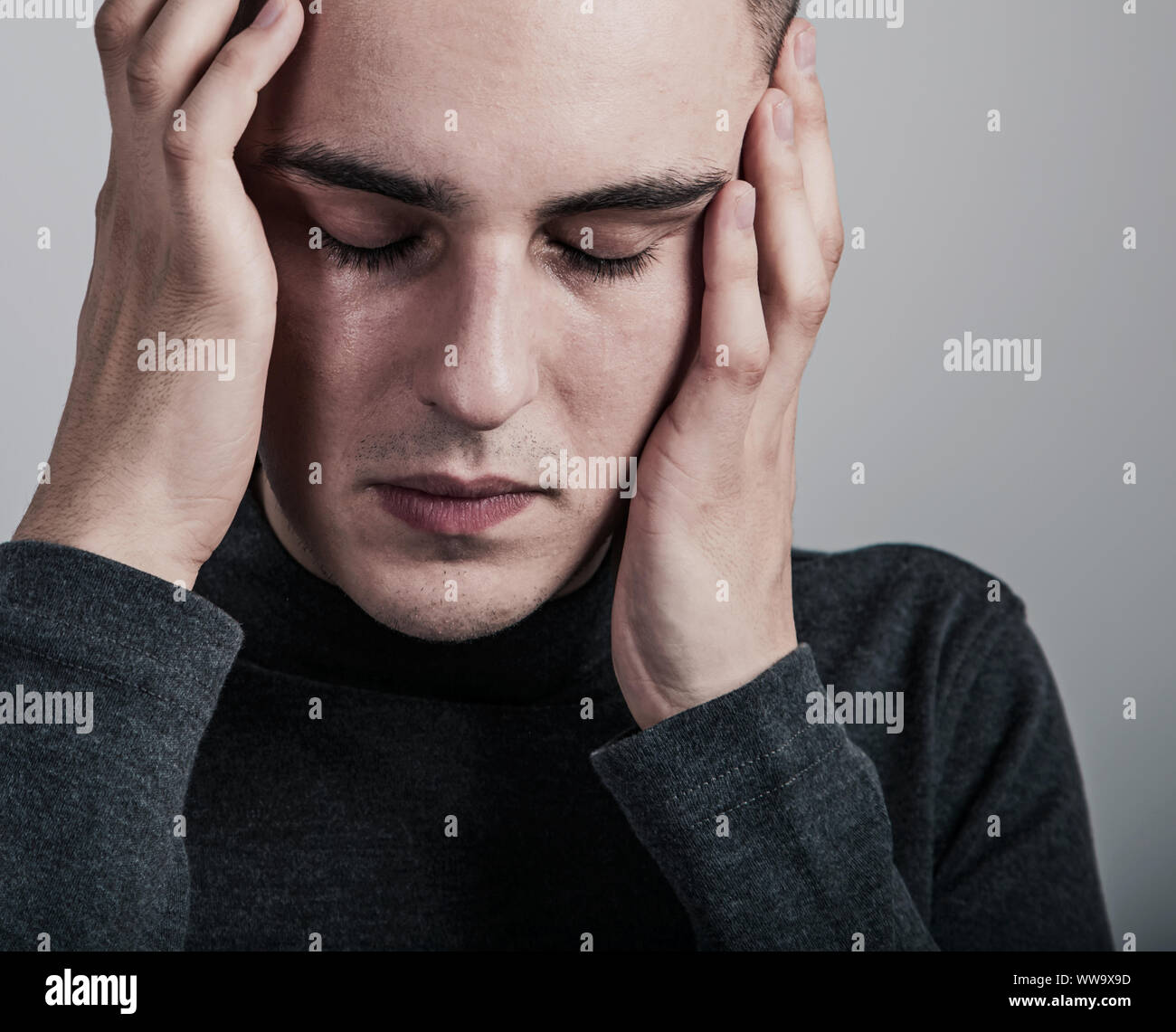 Unhappy crying ill man with headache holding the head. Closeup studio ...