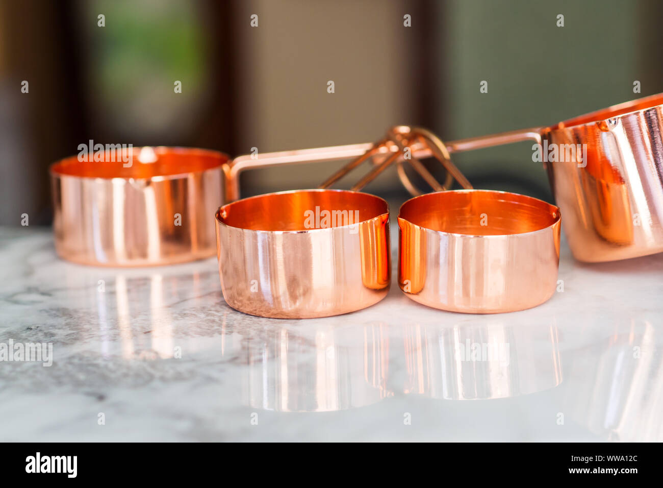 Copper measuring cups on marble table in the kitchen. Ready to cook or ...