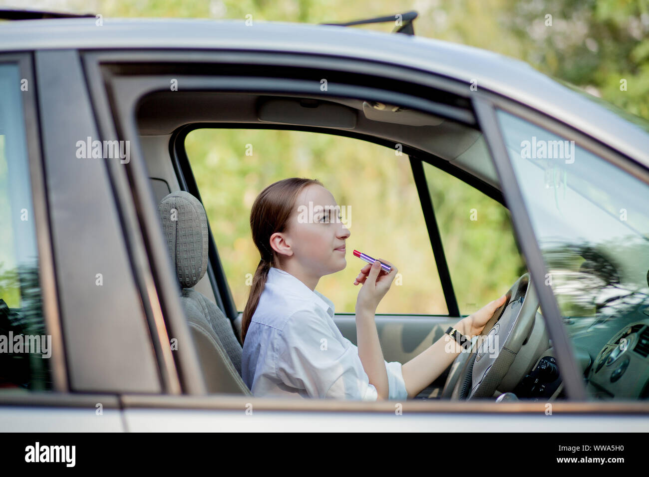 Picture of young businesswoman doing makeup while driving a car in the ...