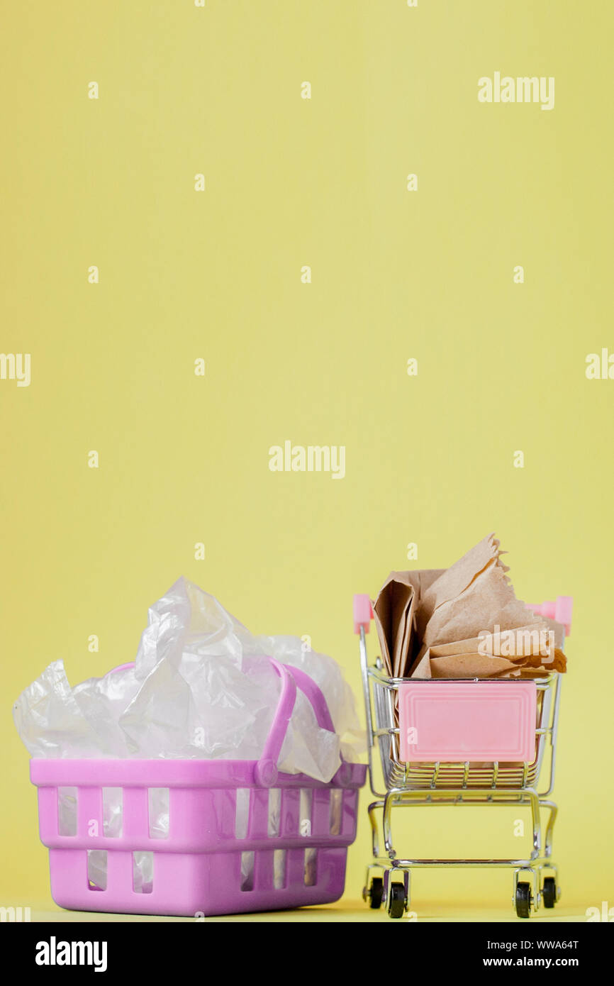 polythene and paper bags in a shopping basket on a yellow background ...