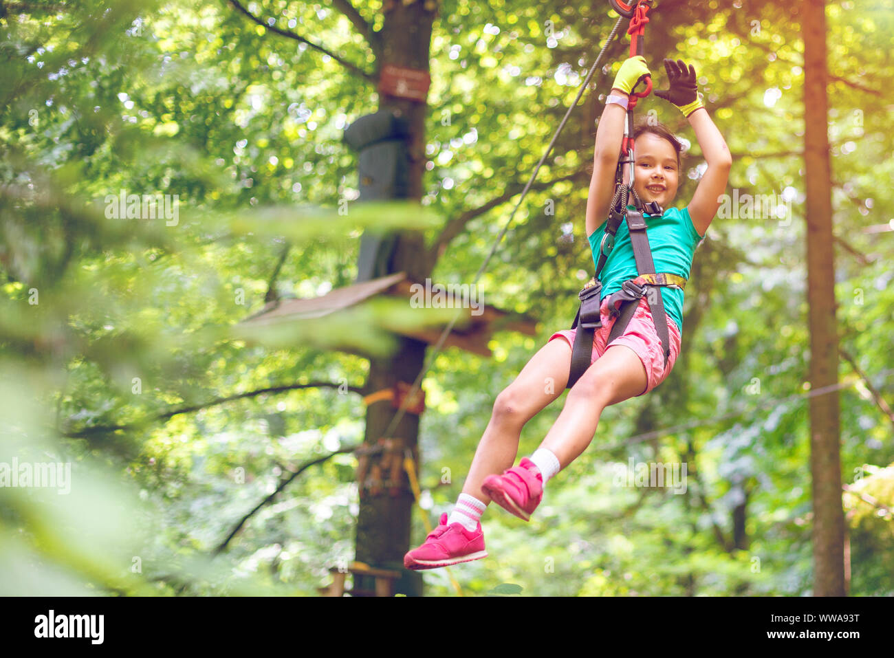 Happy little girl on zip line between trees Stock Photo - Alamy