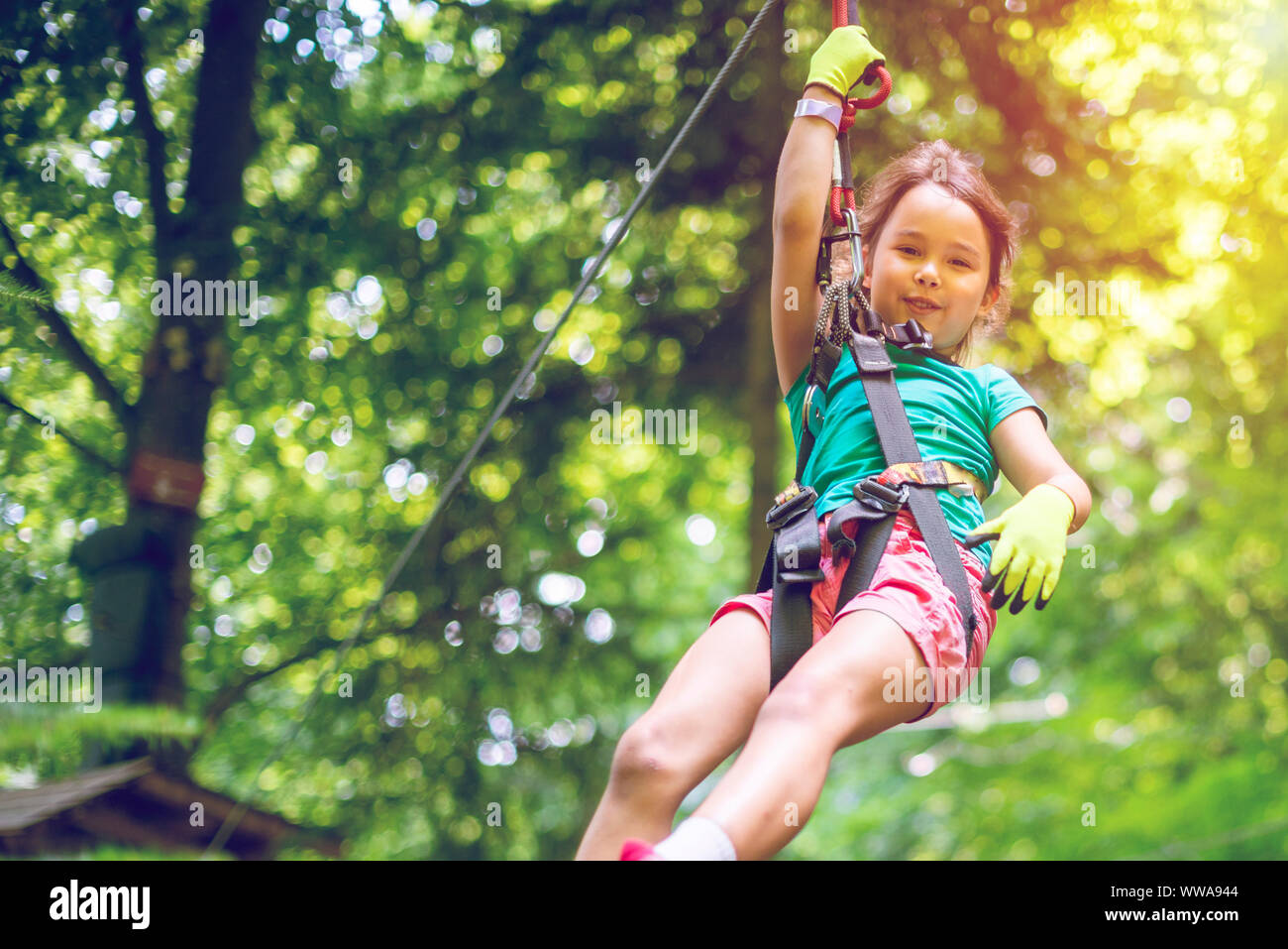 Happy little girl on zip line between trees Stock Photo - Alamy