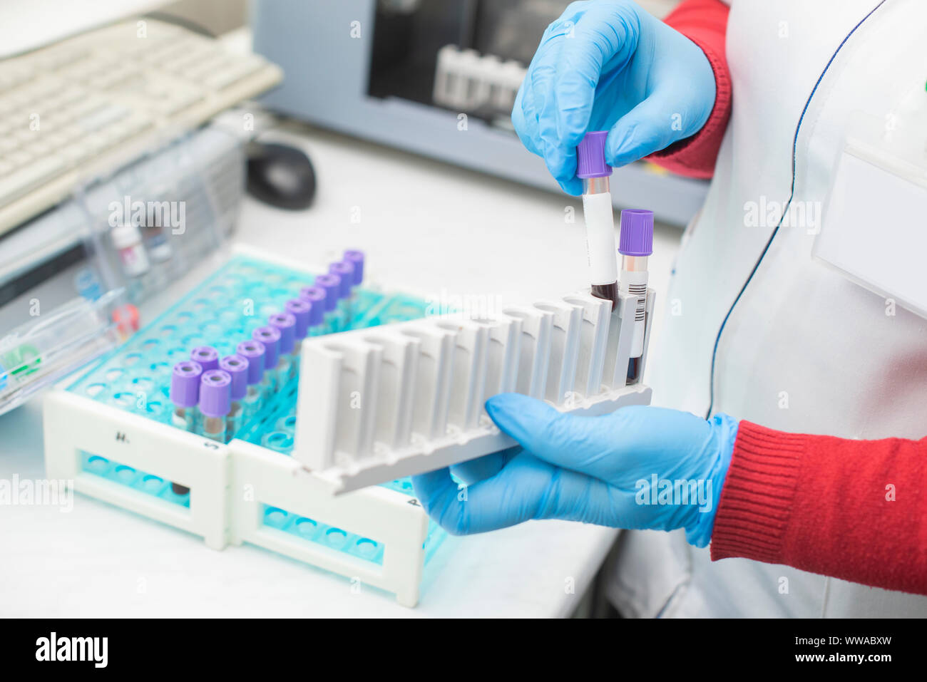 doctor hand taking a blood sample tube from a rack with machines of ...
