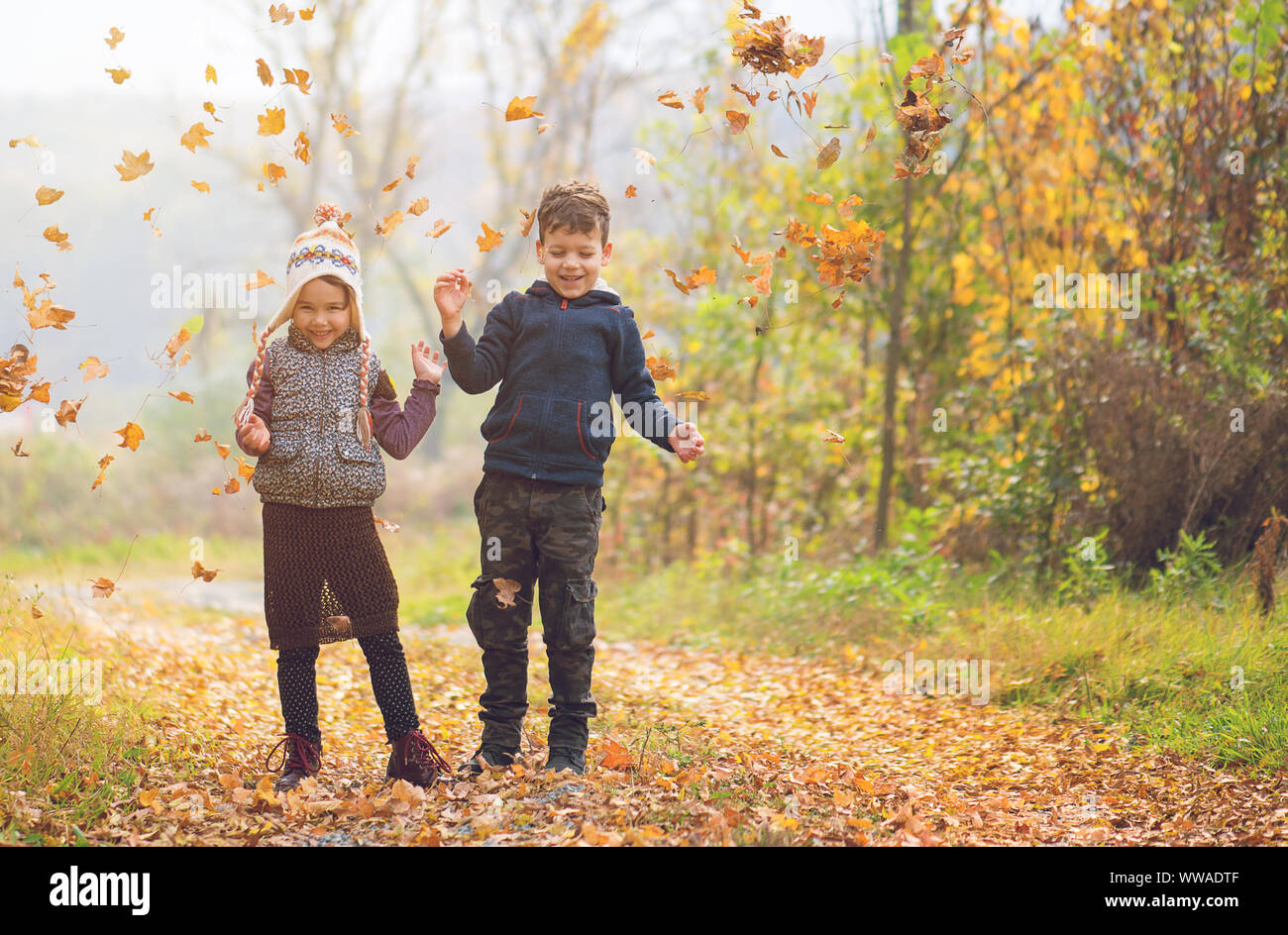 Children playing with autumn fallen leaves in park Stock Photo - Alamy