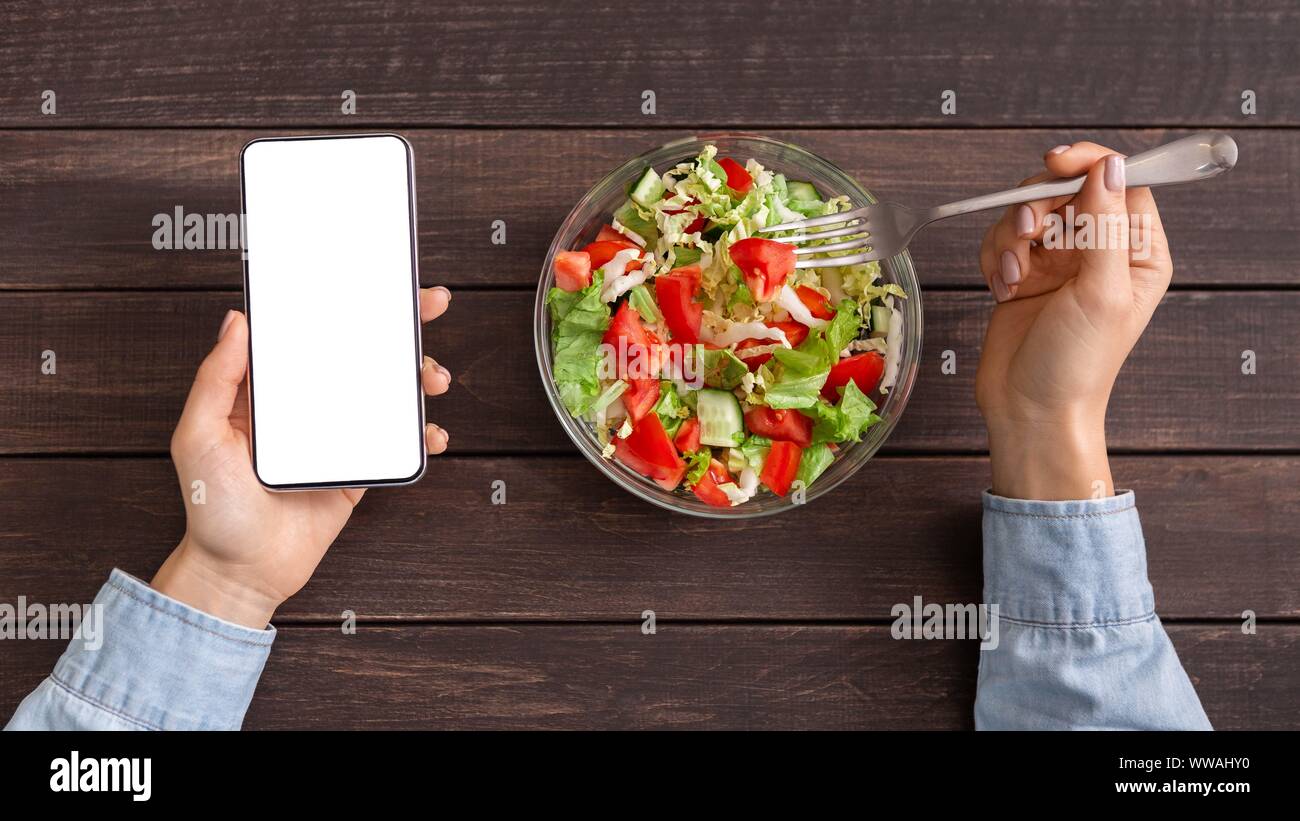Woman using smartphone with blank screen and eating fresh salad Stock ...