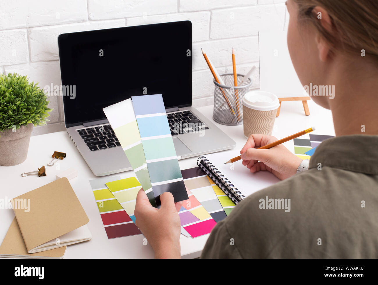 Young woman designer writing down colors to buy for clients Stock Photo ...