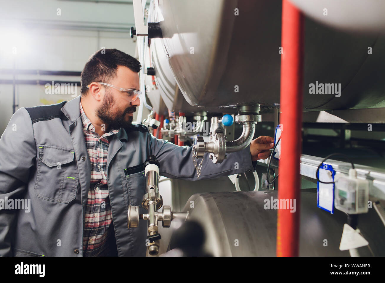Portrait of brewer who is making beer on his workplace in the brew ...