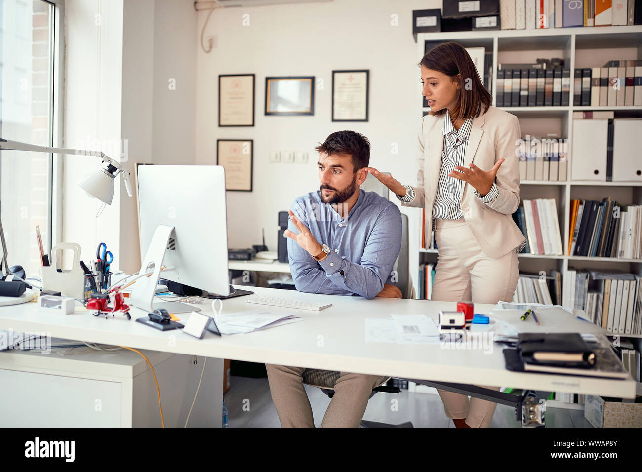 Young man and woman at work working and looking at computer screen in ...