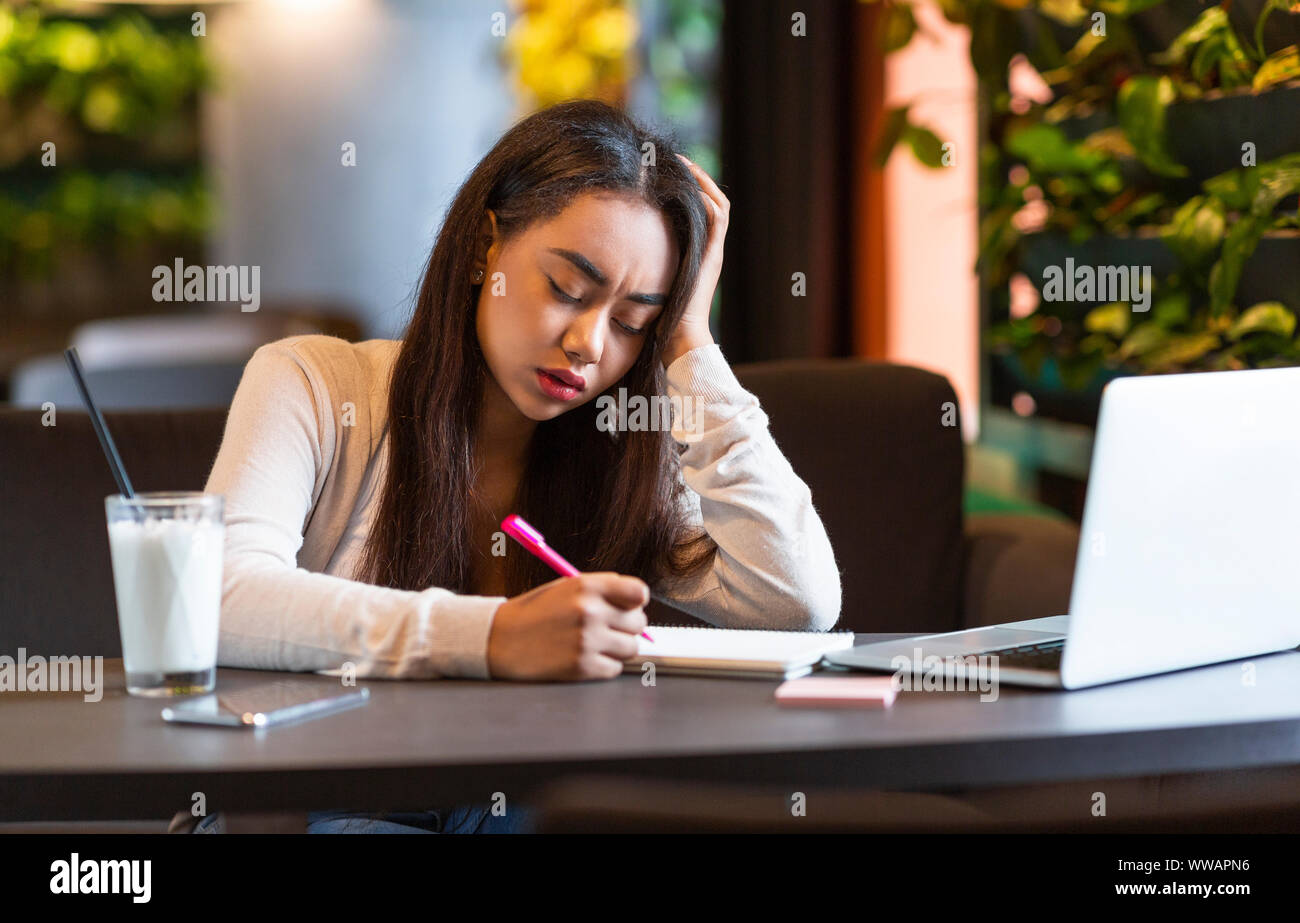 Tired teen girl making notes while studying Stock Photo - Alamy