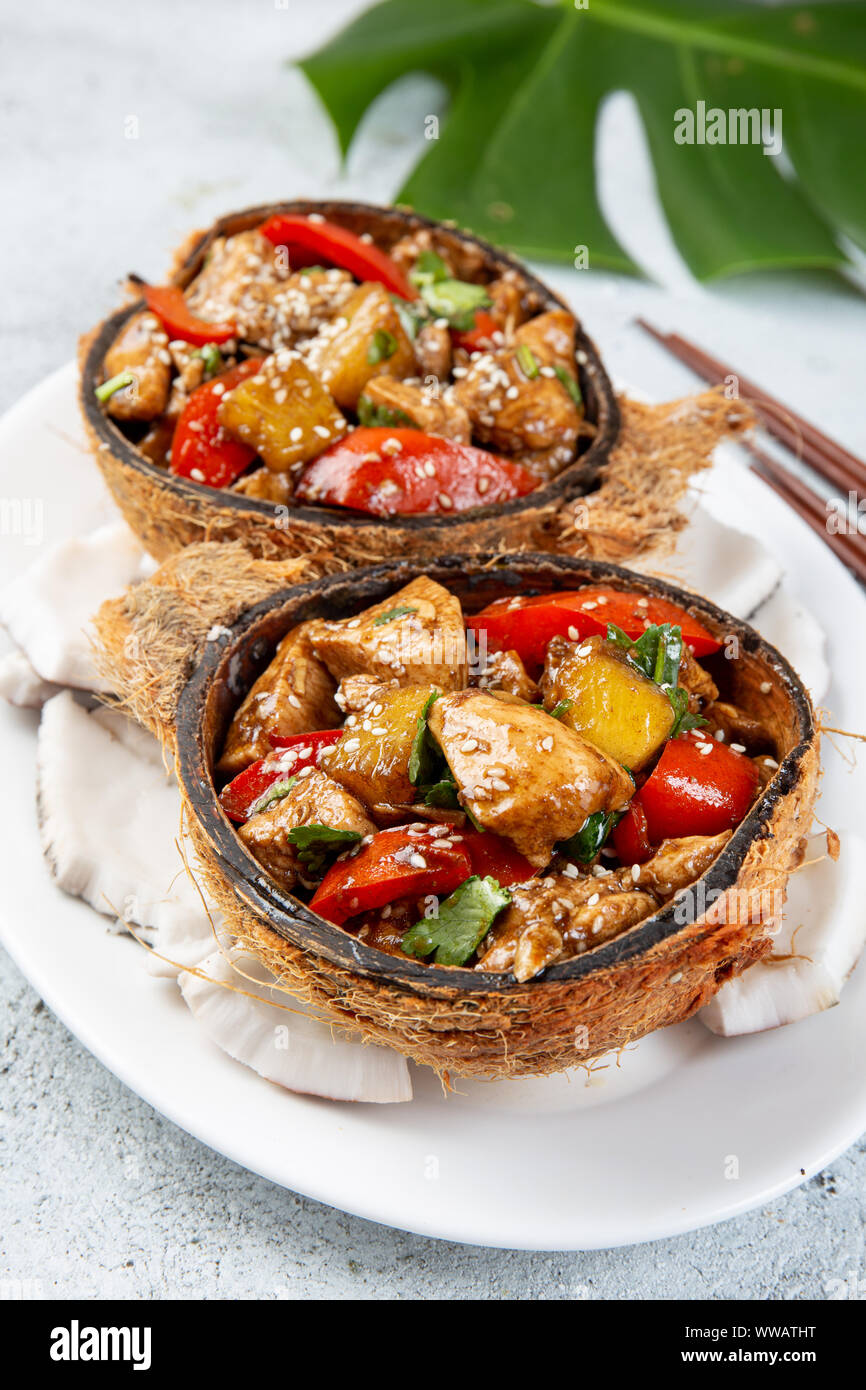 Hawaiian pinapple chicken in natural coconut shell plates on white ...