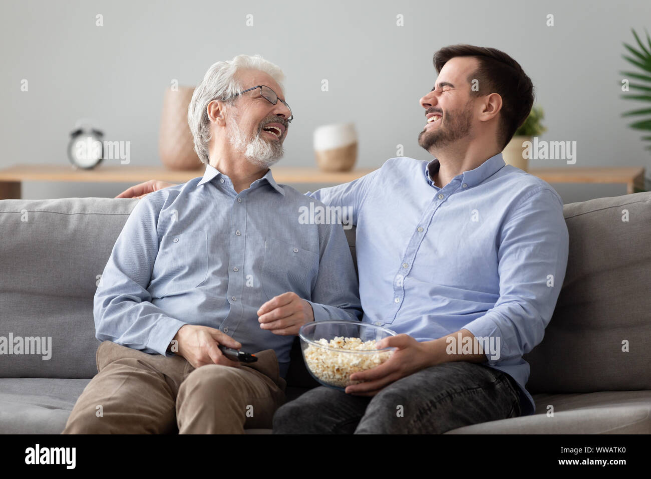 Happy two generations male family laugh enjoy talk watching television ...
