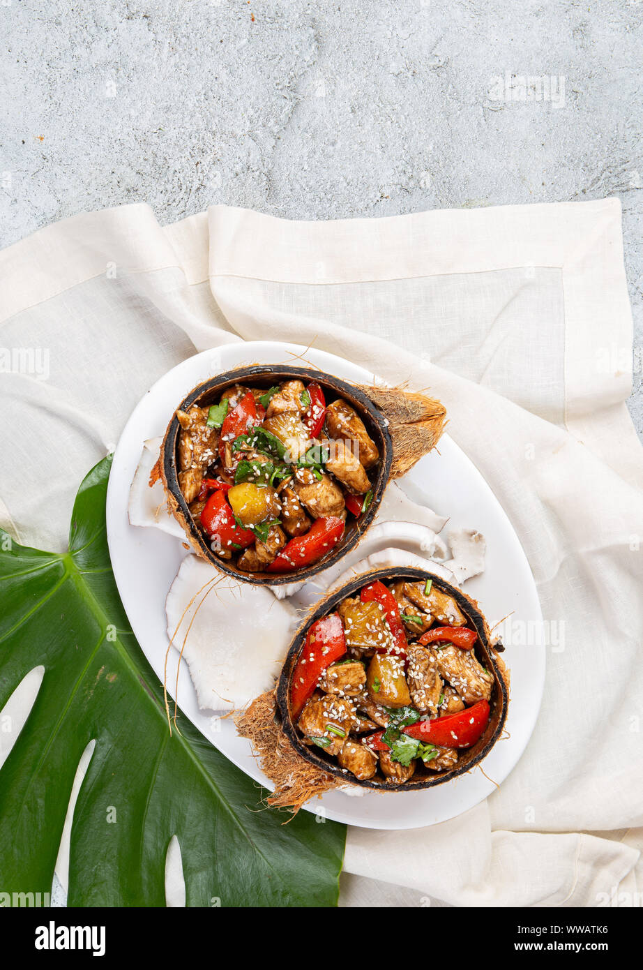 Hawaiian pinapple chicken in natural coconut shell plates on white ...