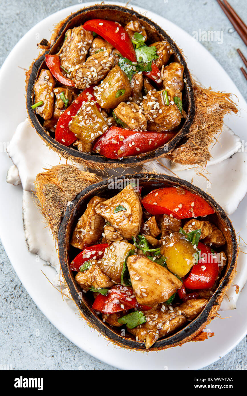 Hawaiian pinapple chicken in natural coconut shell plates on white ...