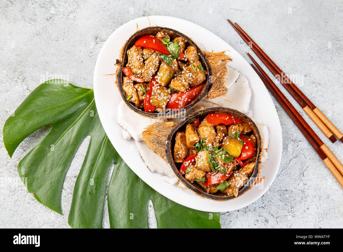 Hawaiian pinapple chicken in natural coconut shell plates on white ...