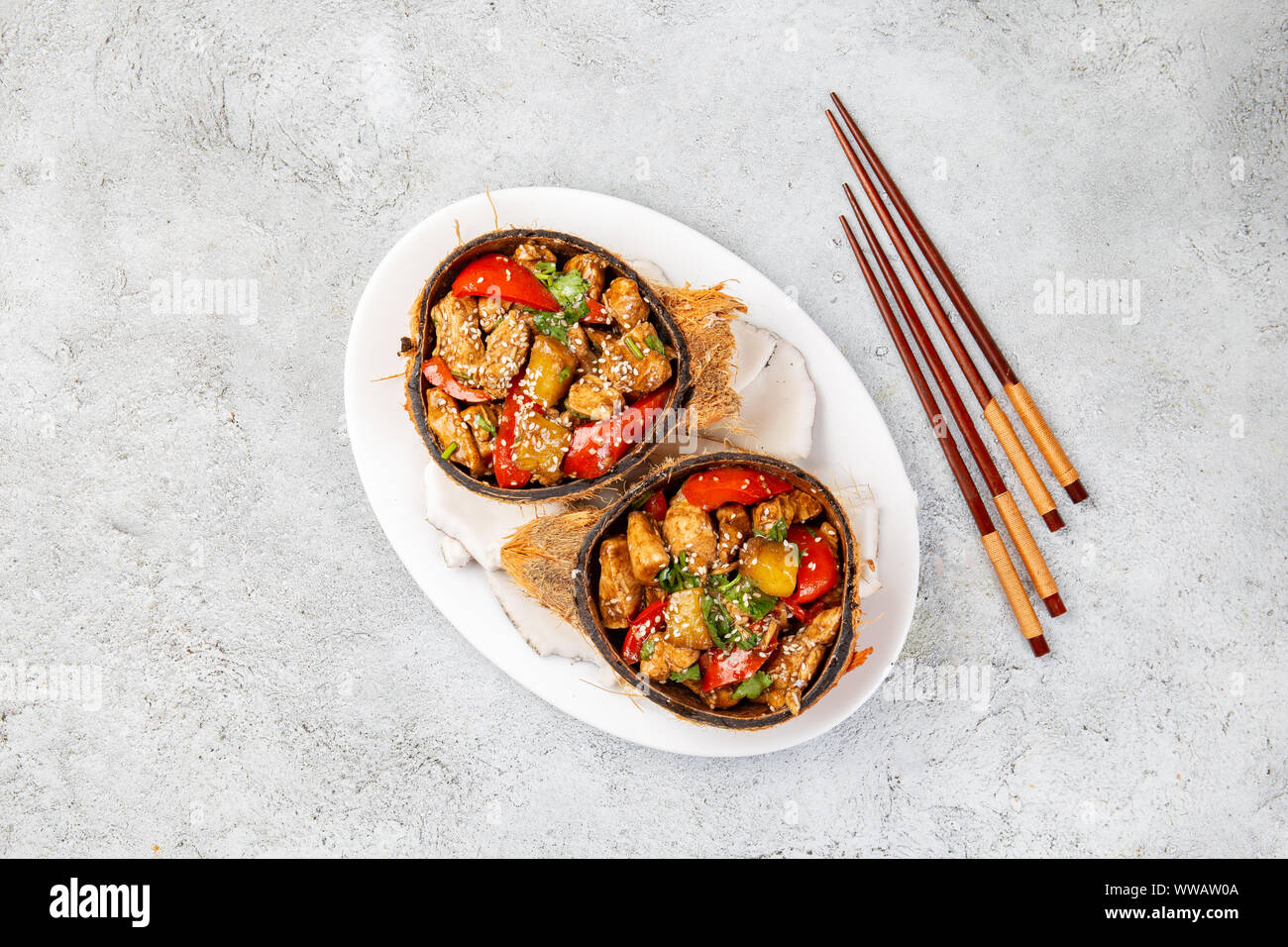 Hawaiian pinapple chicken in natural coconut shell plates on white ...