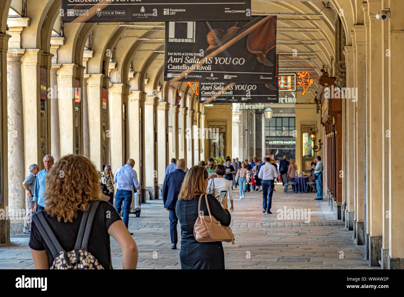 People walking through an elegant portico at Piazza San Carlo in Turin ...