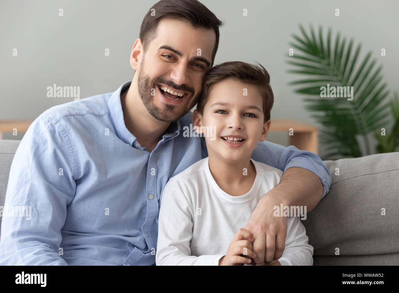 Happy dad embracing son looking at camera sit on sofa Stock Photo - Alamy