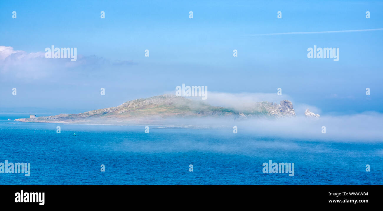 Low lying fog or mist approaching and covering Irelands Eye island ...