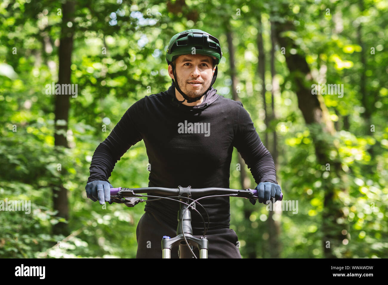 Excited cyclist looking forward over forest background Stock Photo - Alamy