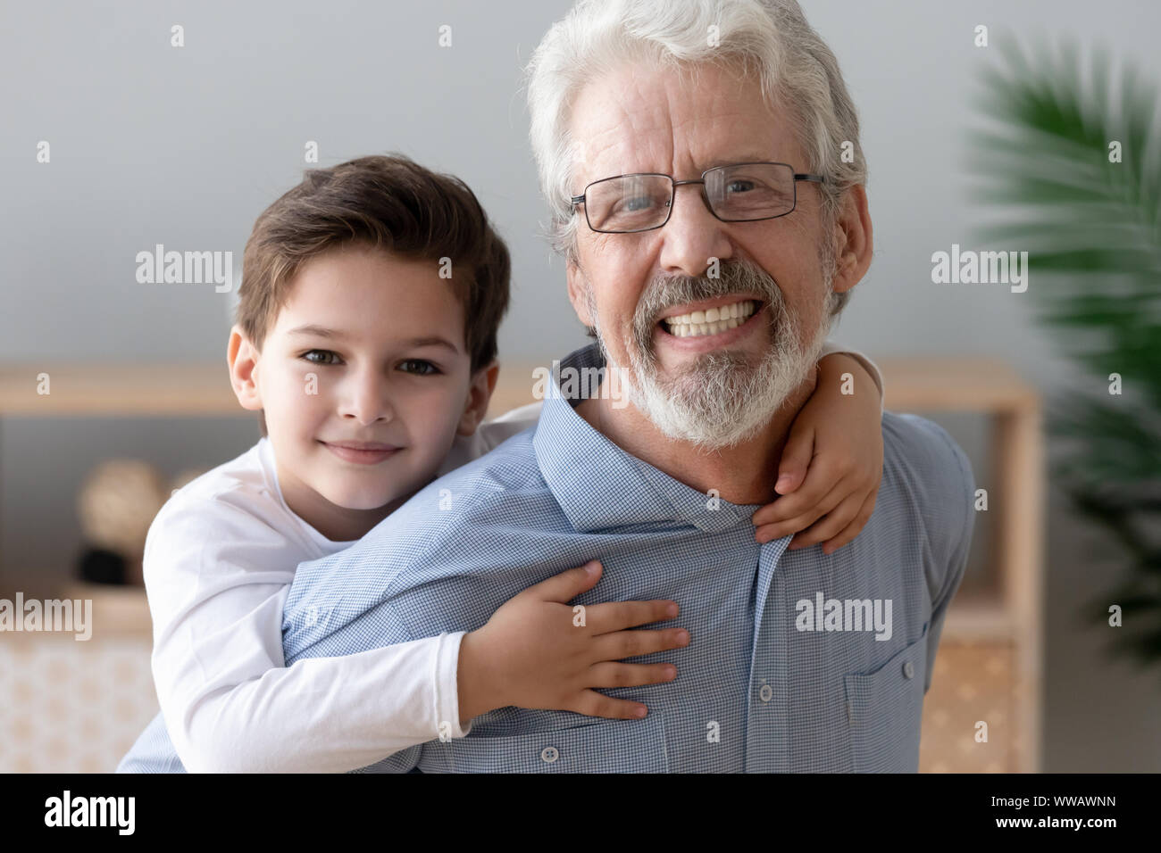 Happy old grandfather piggyback little grandson look at camera Stock ...