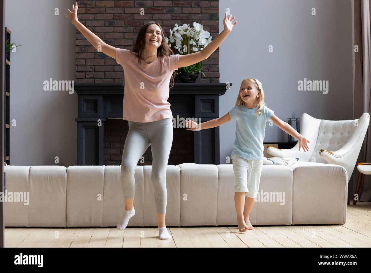 Full length overjoyed millennial mother dancing with little preschool ...
