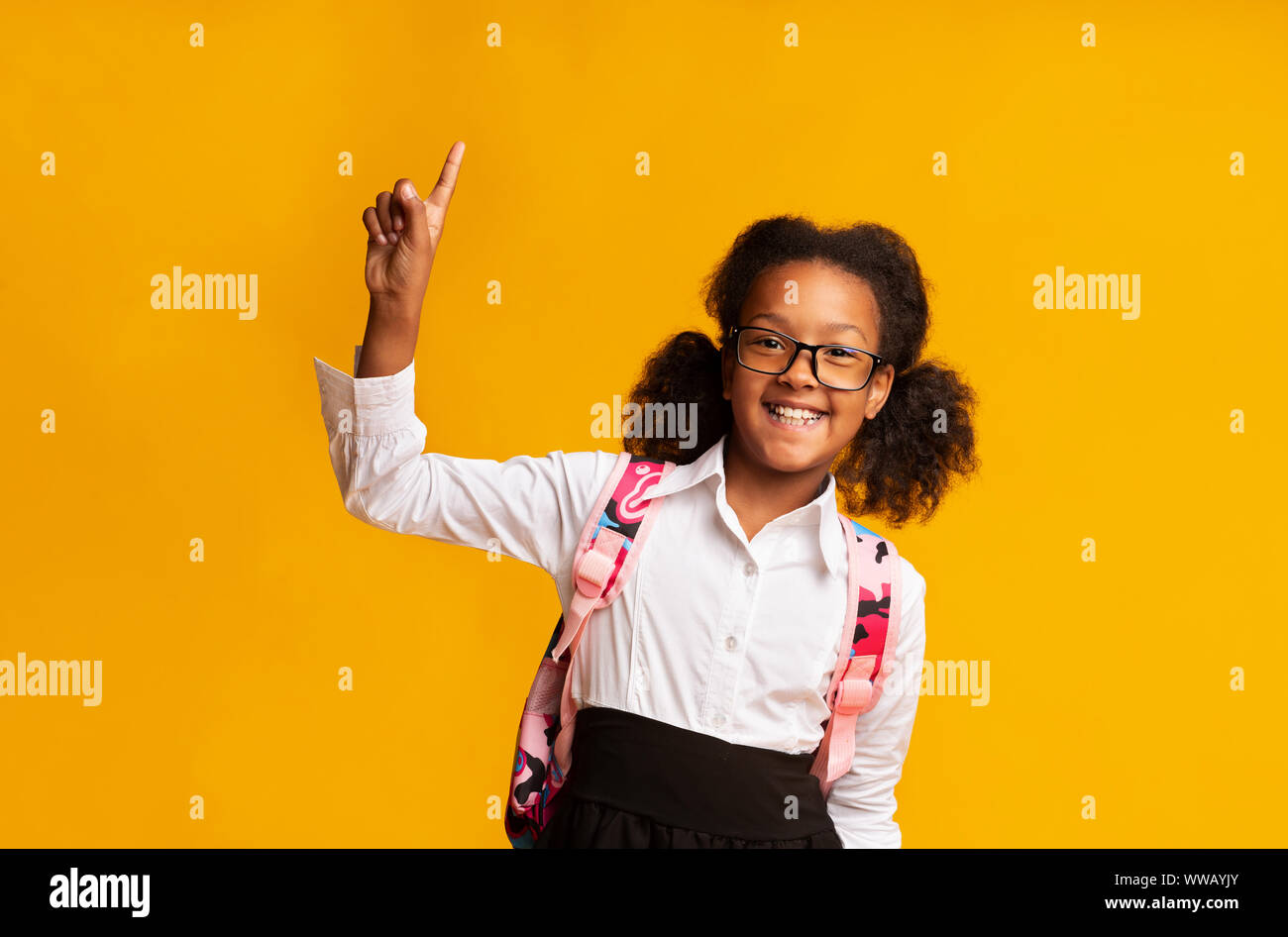 African American Schoolgirl Pointing Finger Up On Yellow Background ...
