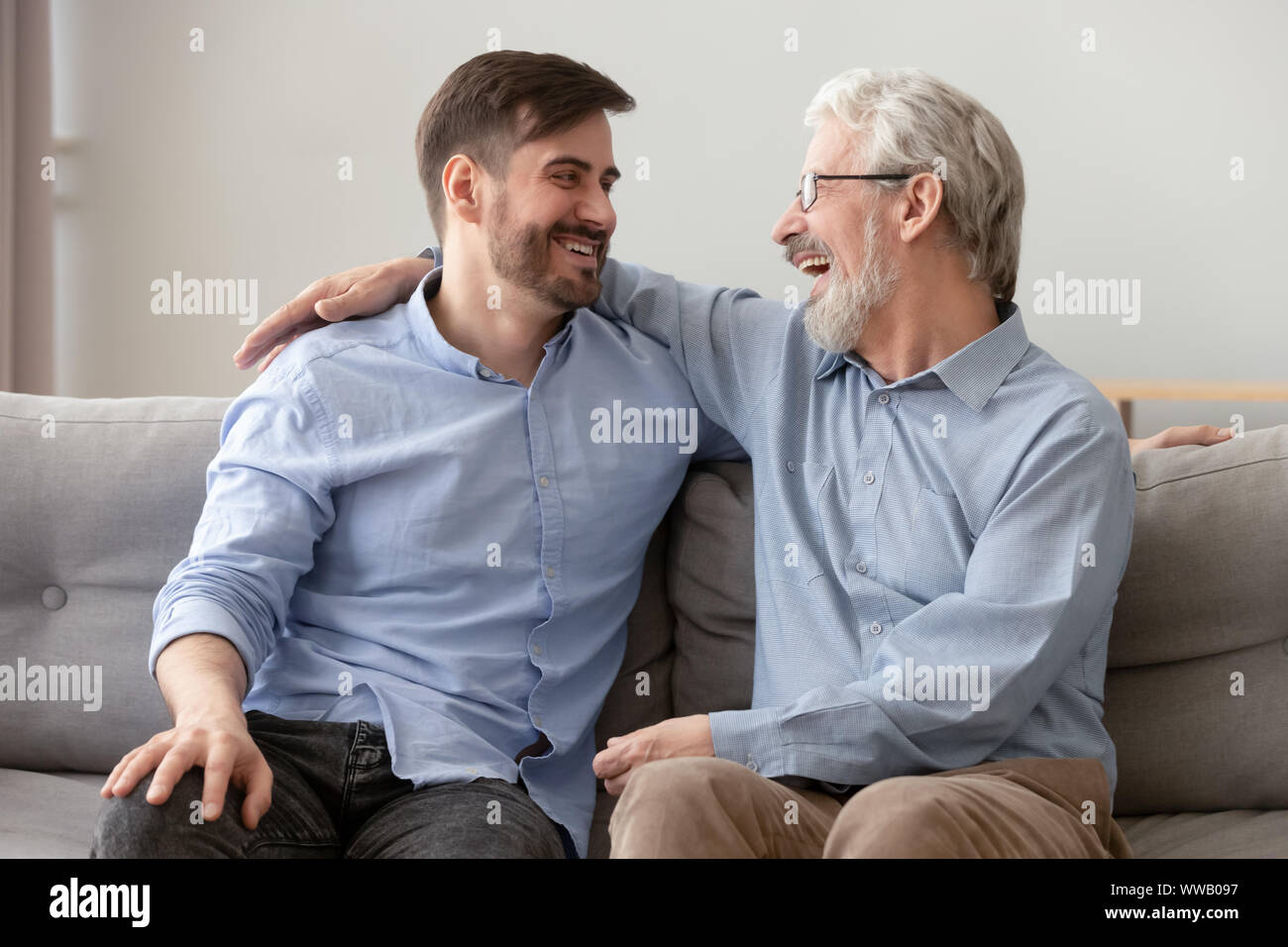 Happy old dad embracing young son talking laughing on sofa Stock Photo ...