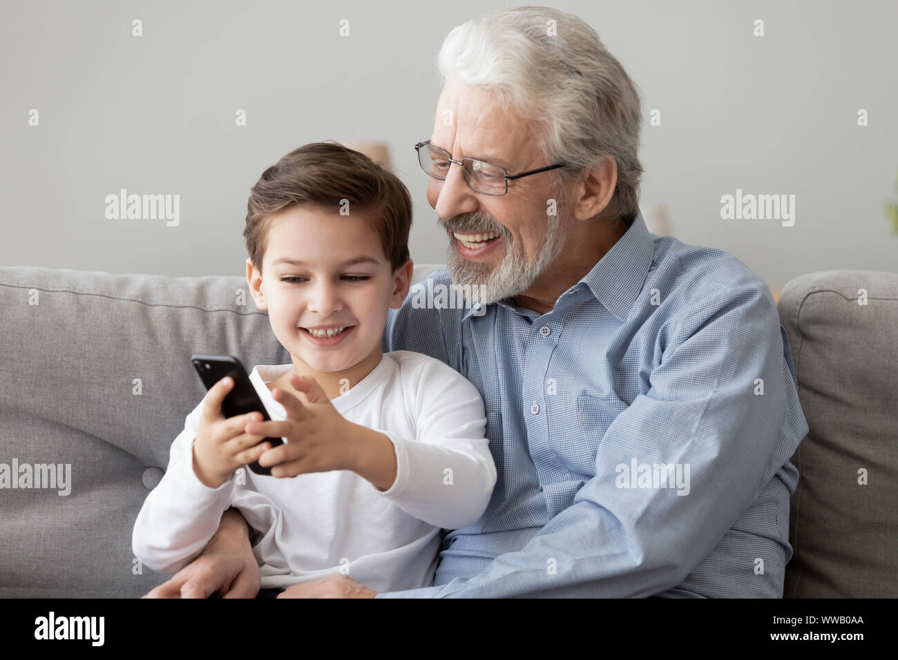 Happy senior grandfather and grandson using smart phone at home Stock ...
