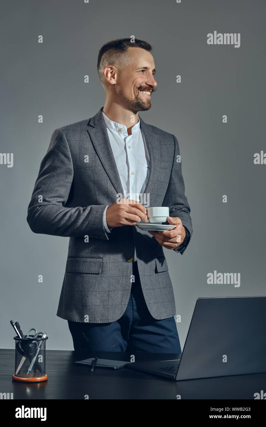 Bearded businessman with stylish mustache, dressed in a classic suit is ...