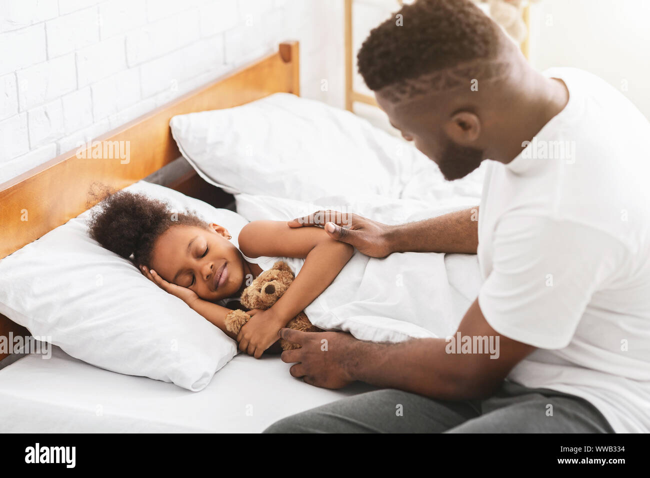 Caring african dad putting his little daughter to sleep Stock Photo - Alamy