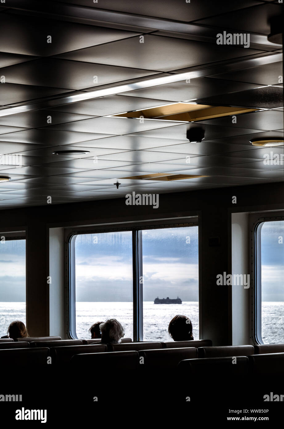 Silhouettes of indoor boat passengers seated beside window looking ...