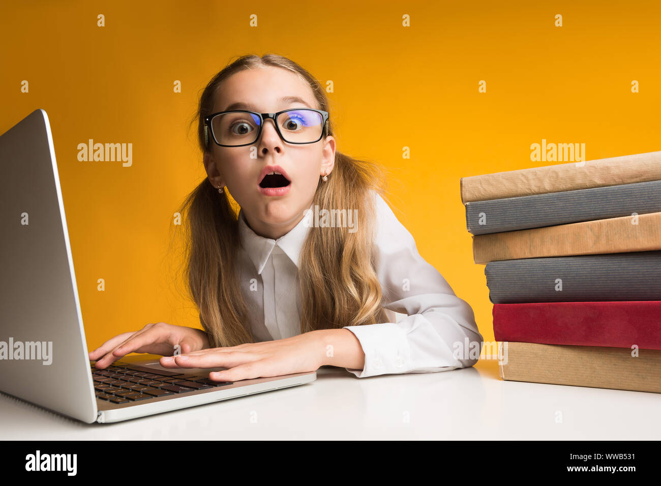 Shocked Elementary Student Girl Doing Homework On Laptop, Studio Shot ...